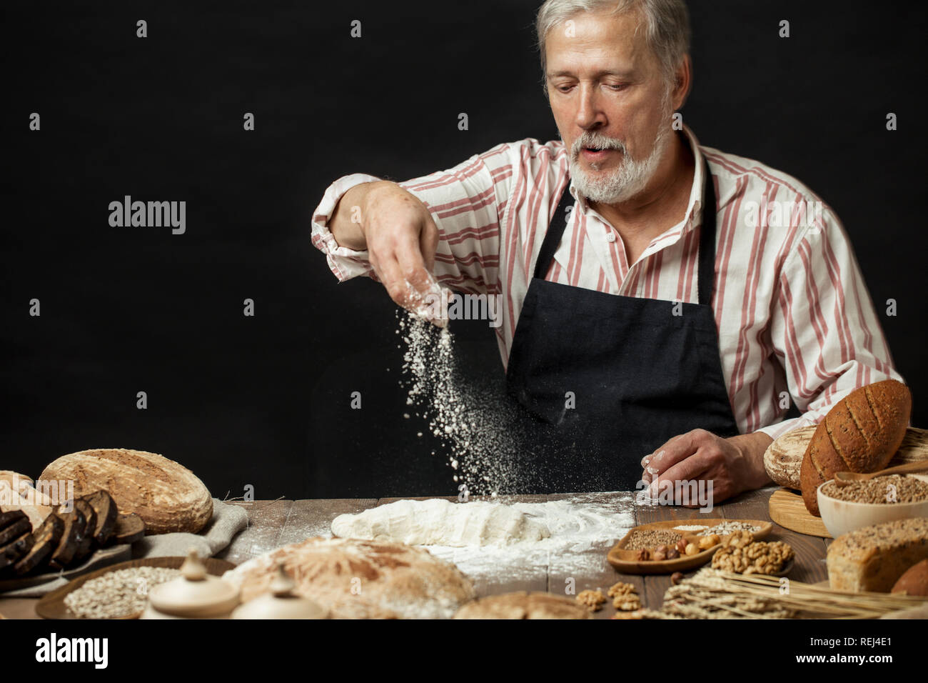 Man sprinkling some flour on dough. Hands kneading dough, cropped view ...