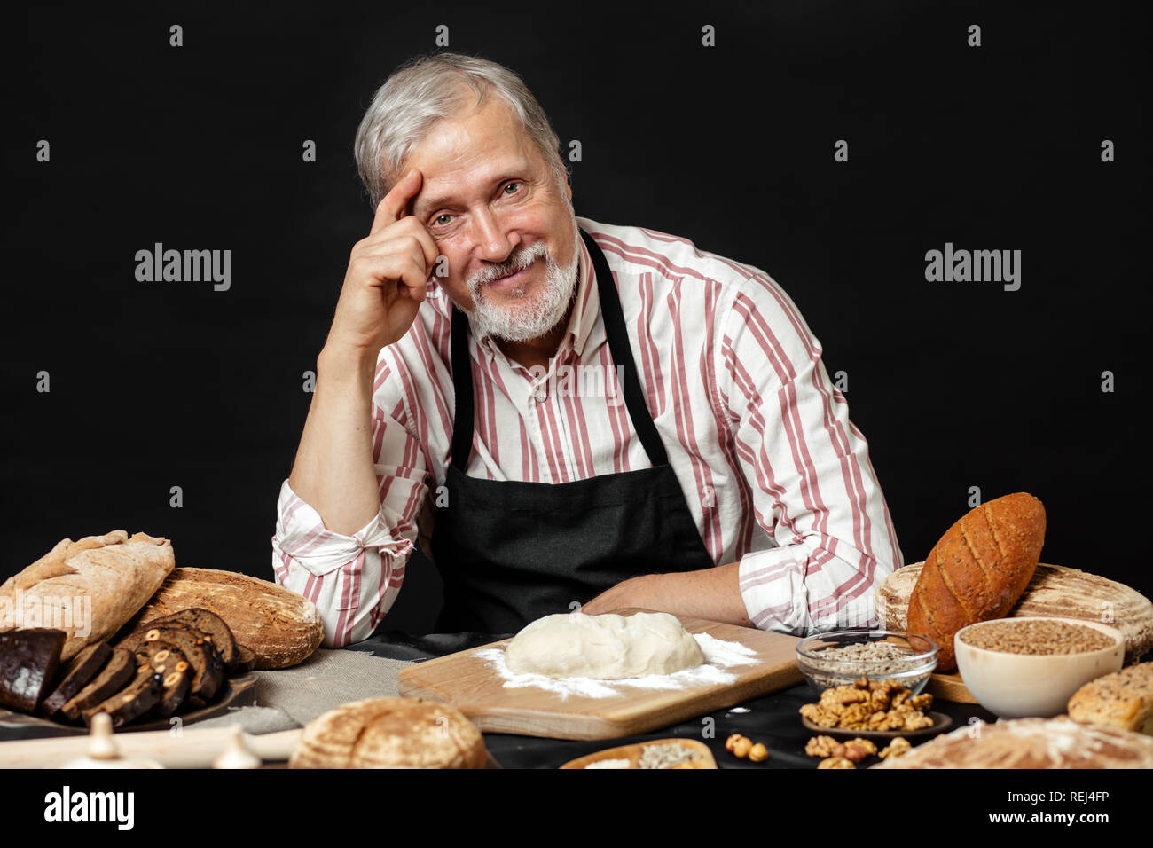 Elderly smiling professional chef man. Isolated over black background ...