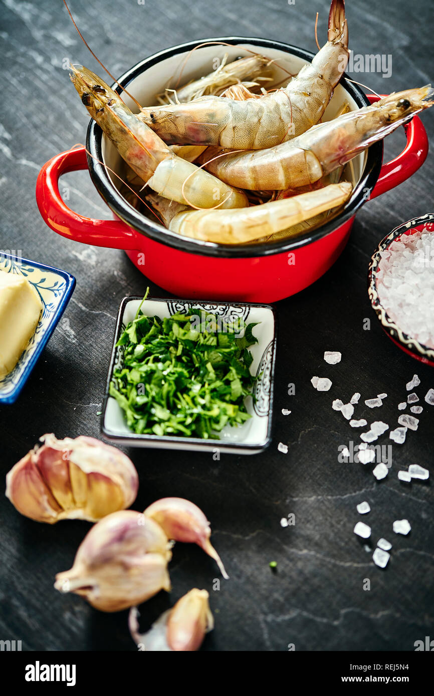 fresh delicious raw tiger prawns in a red pot with parsley, lemon ...