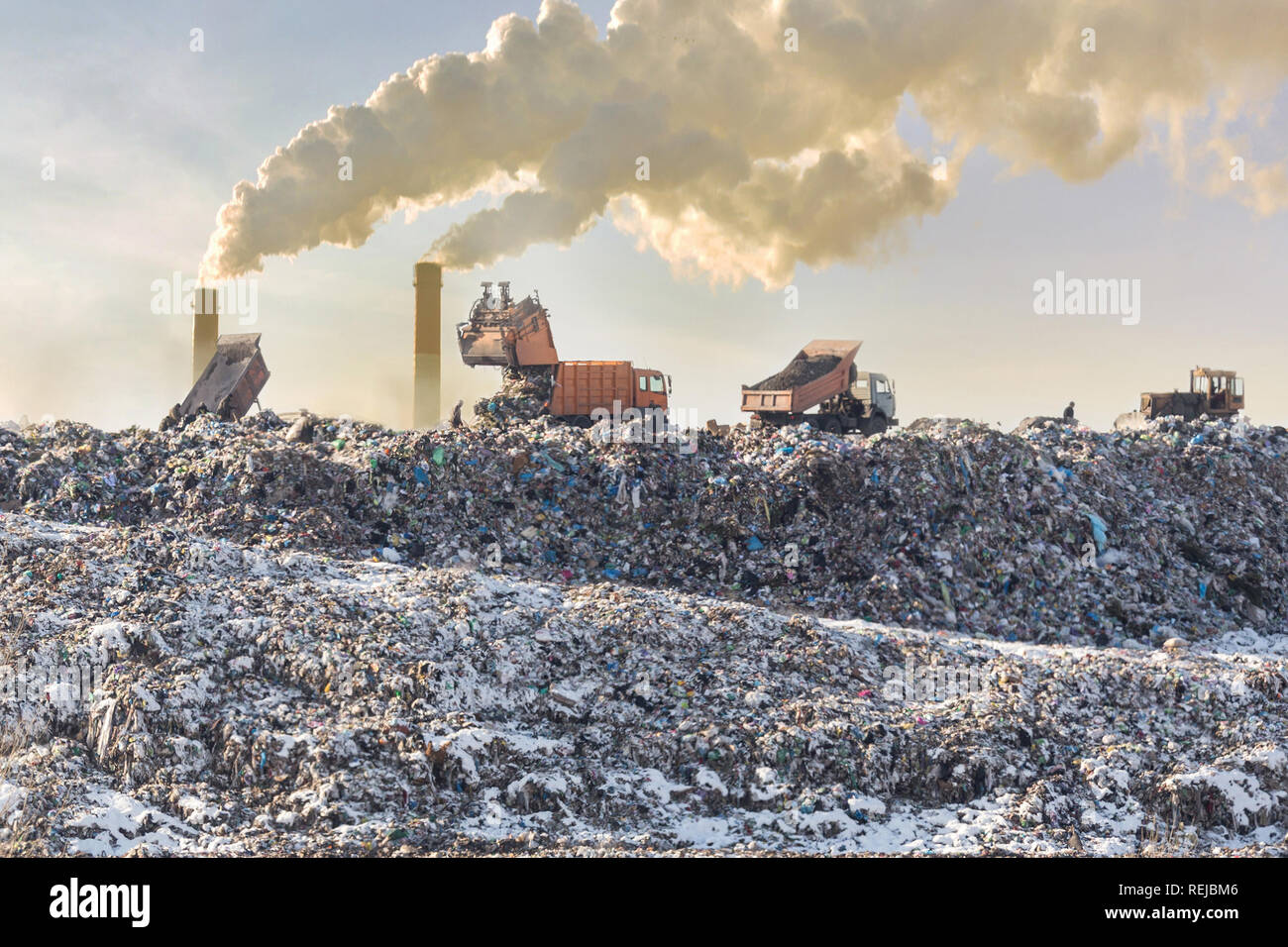 Dump trucks unloading garbage over vast landfill. Smoking industrial ...