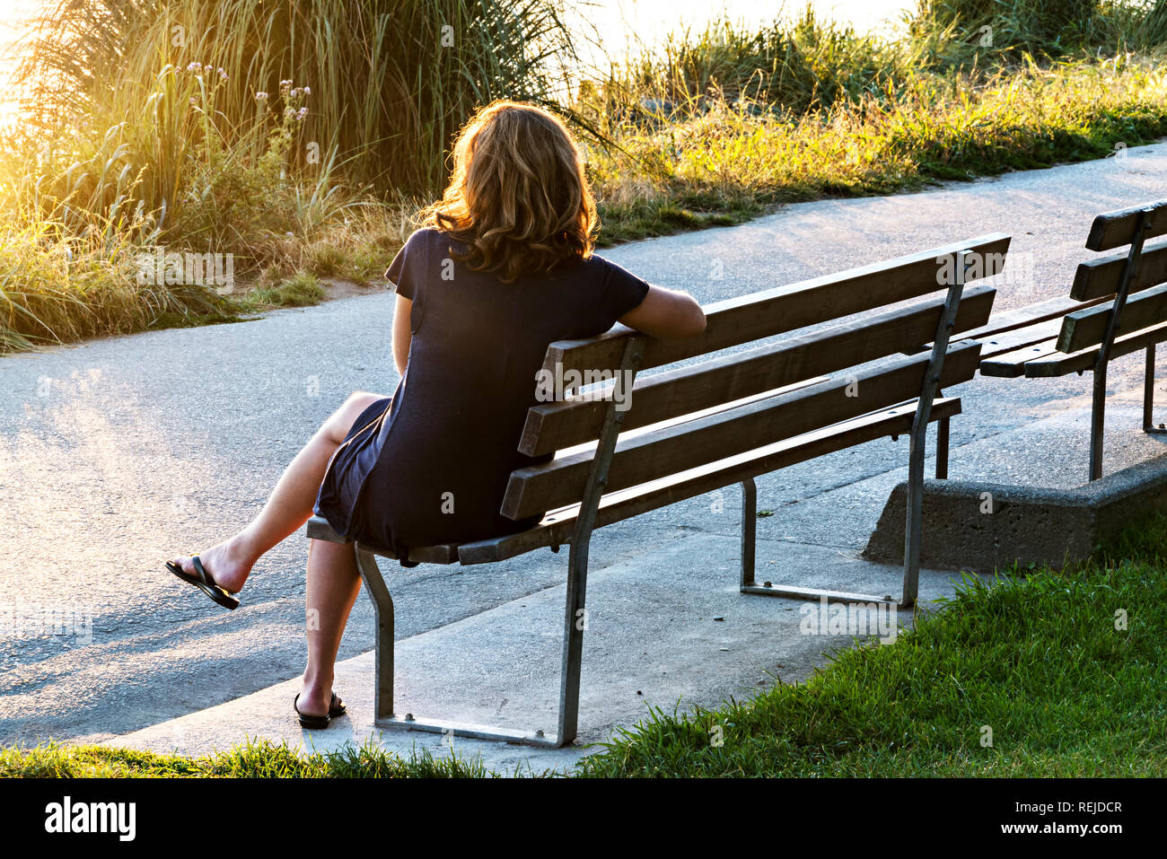 Sun Lit Woman On Bench Stock Photo - Alamy