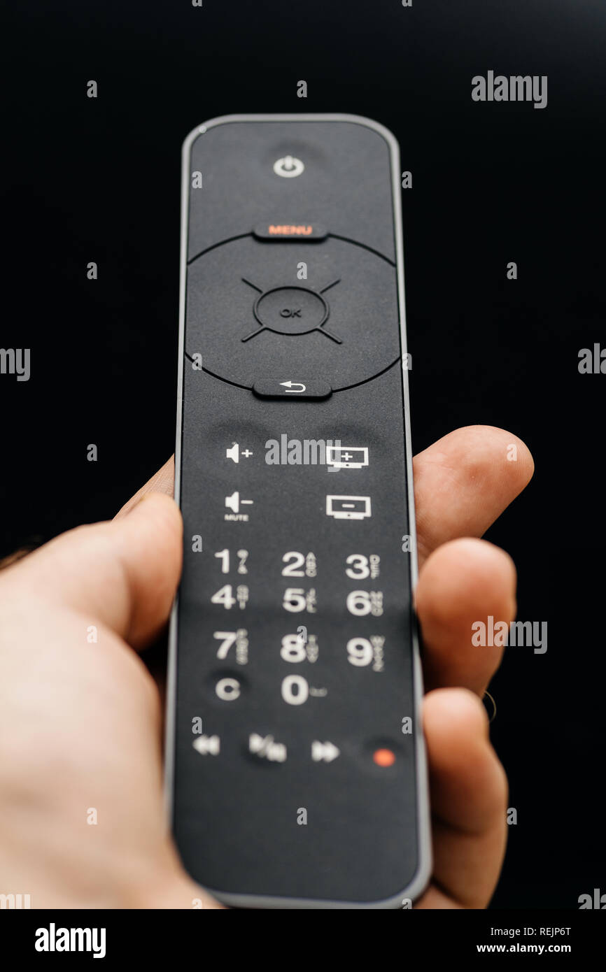 Close-up of manâ s hand holding a modern remote control with multiple ...