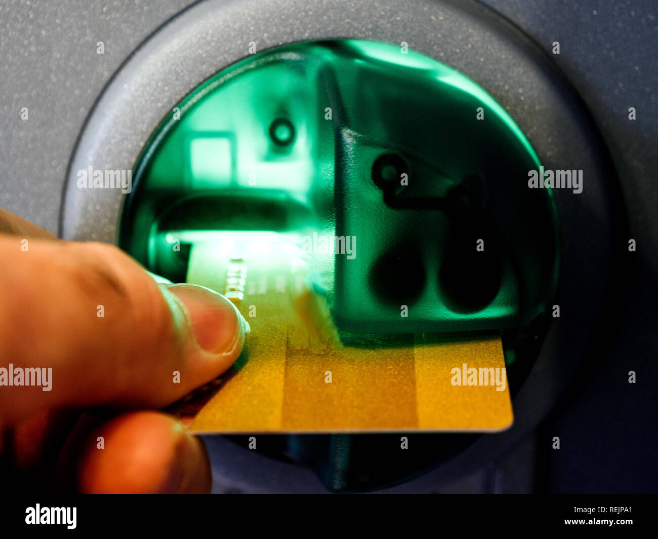 Close-up adult man's hand inserting a debit card into the slot of an automatic teller machine ...