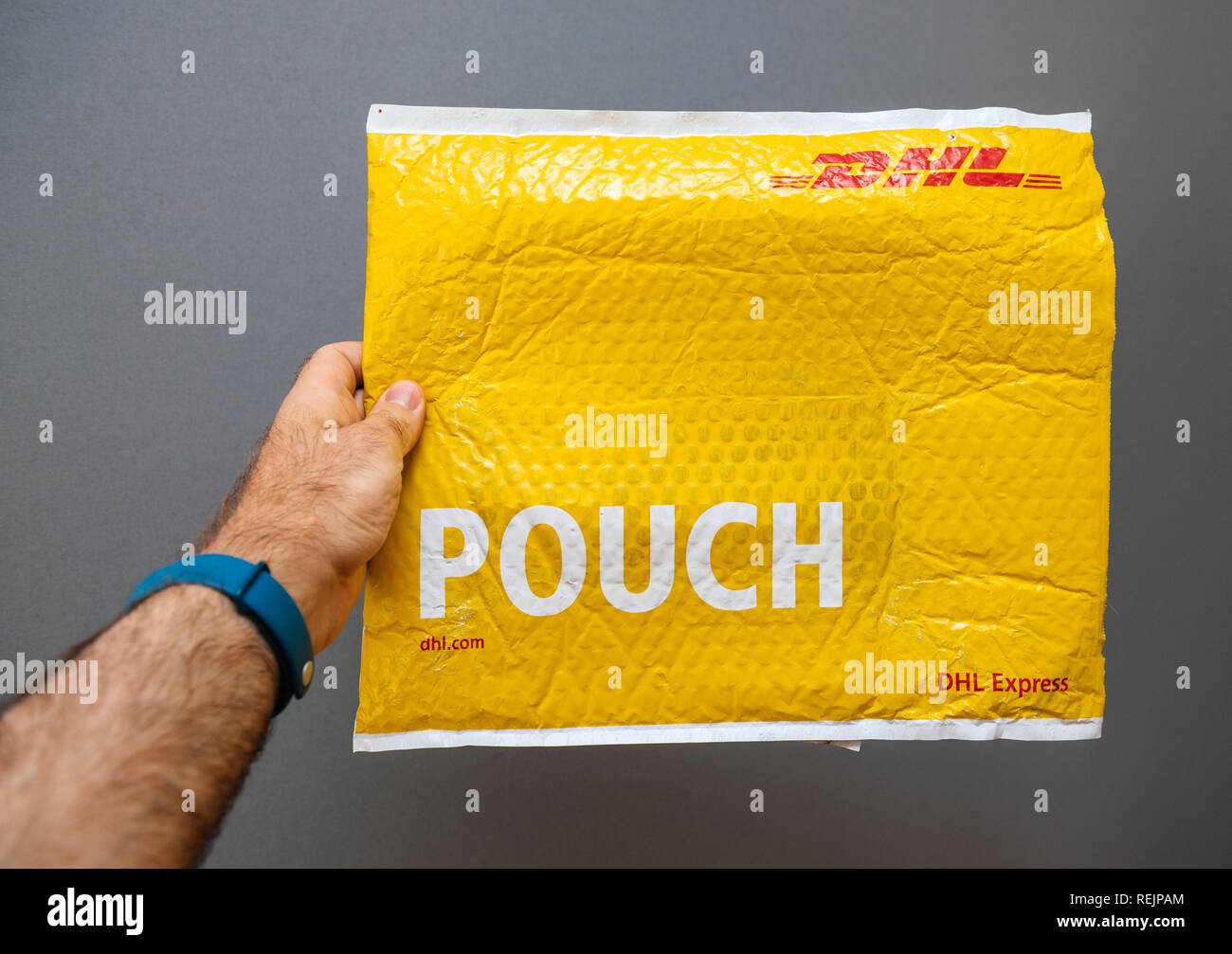 FRANKFURT, GERMANY - MAR 24, 2018: Man holding yellow DHL Express pouch ...