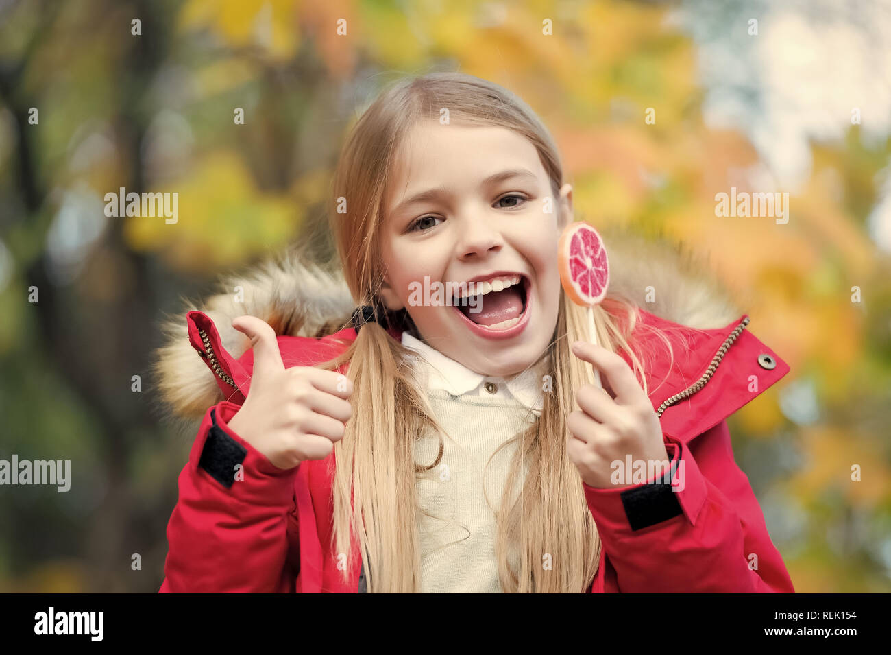 Happy childhood concept. Girl with lollipop show thumbs up on natural ...