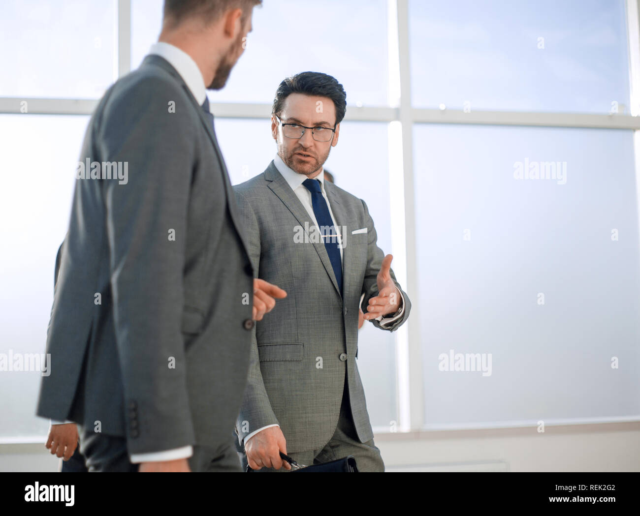 Two businesspeople walking in corridor talking Stock Photo - Alamy