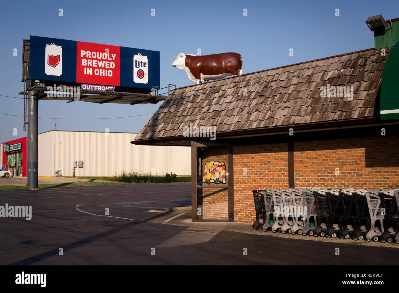 A cow statue on the roof of a meat grocery faces a billboard ...