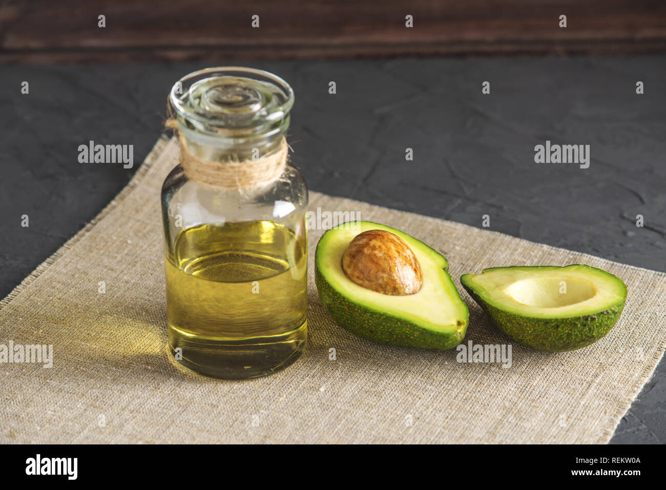 Green avocado fruit and oil in glass bottle on dark background. Concept ...
