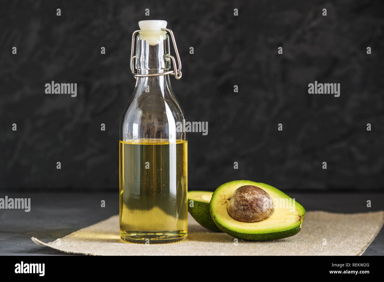 Green avocado fruit and oil in glass bottle on dark background. Concept ...