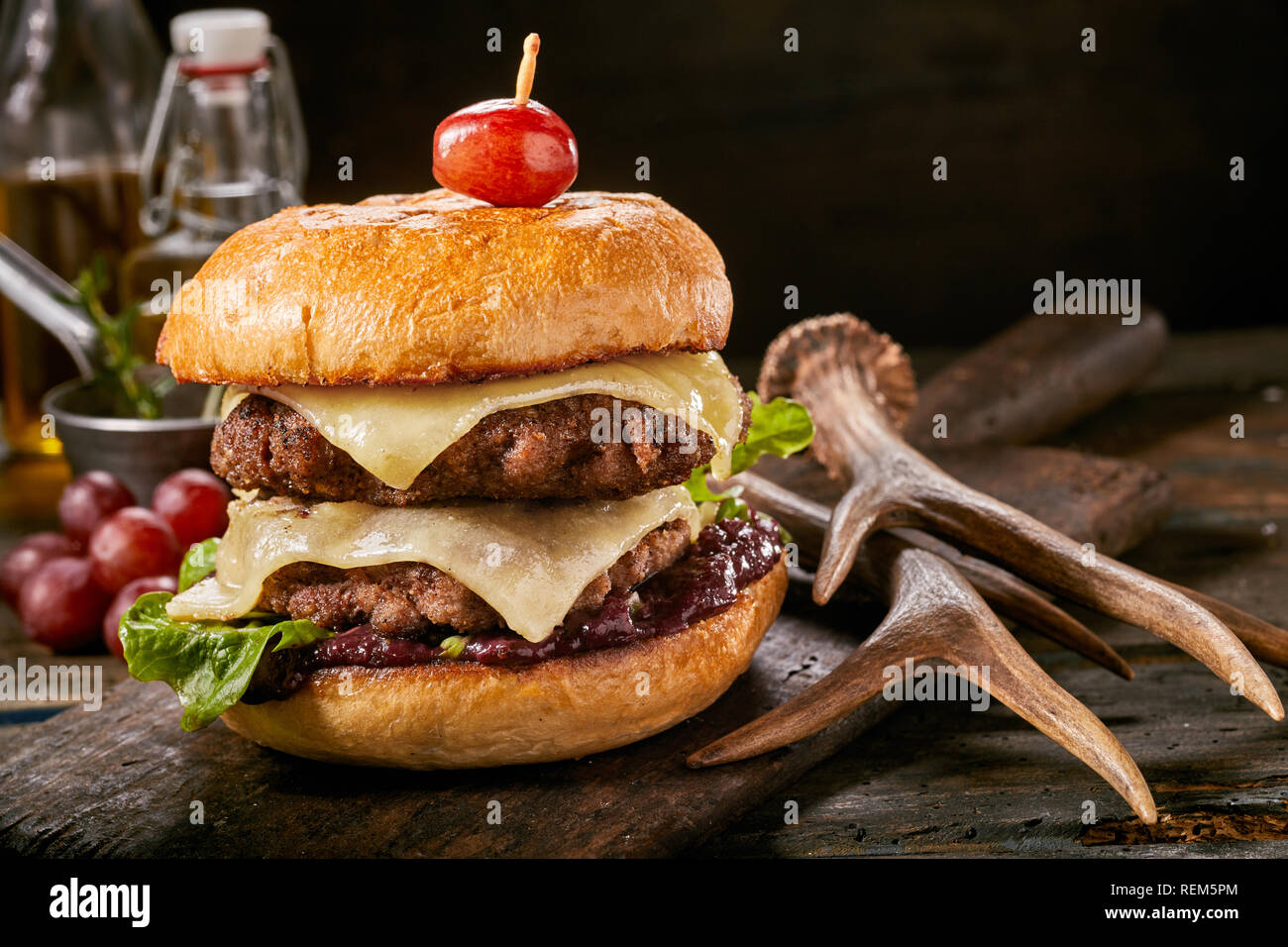 Double decker venison burger with melted cheese on a crusty bun with ...