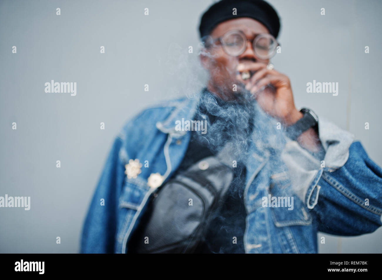 African american man in jeans jacket, beret and eyeglasses, smoking ...