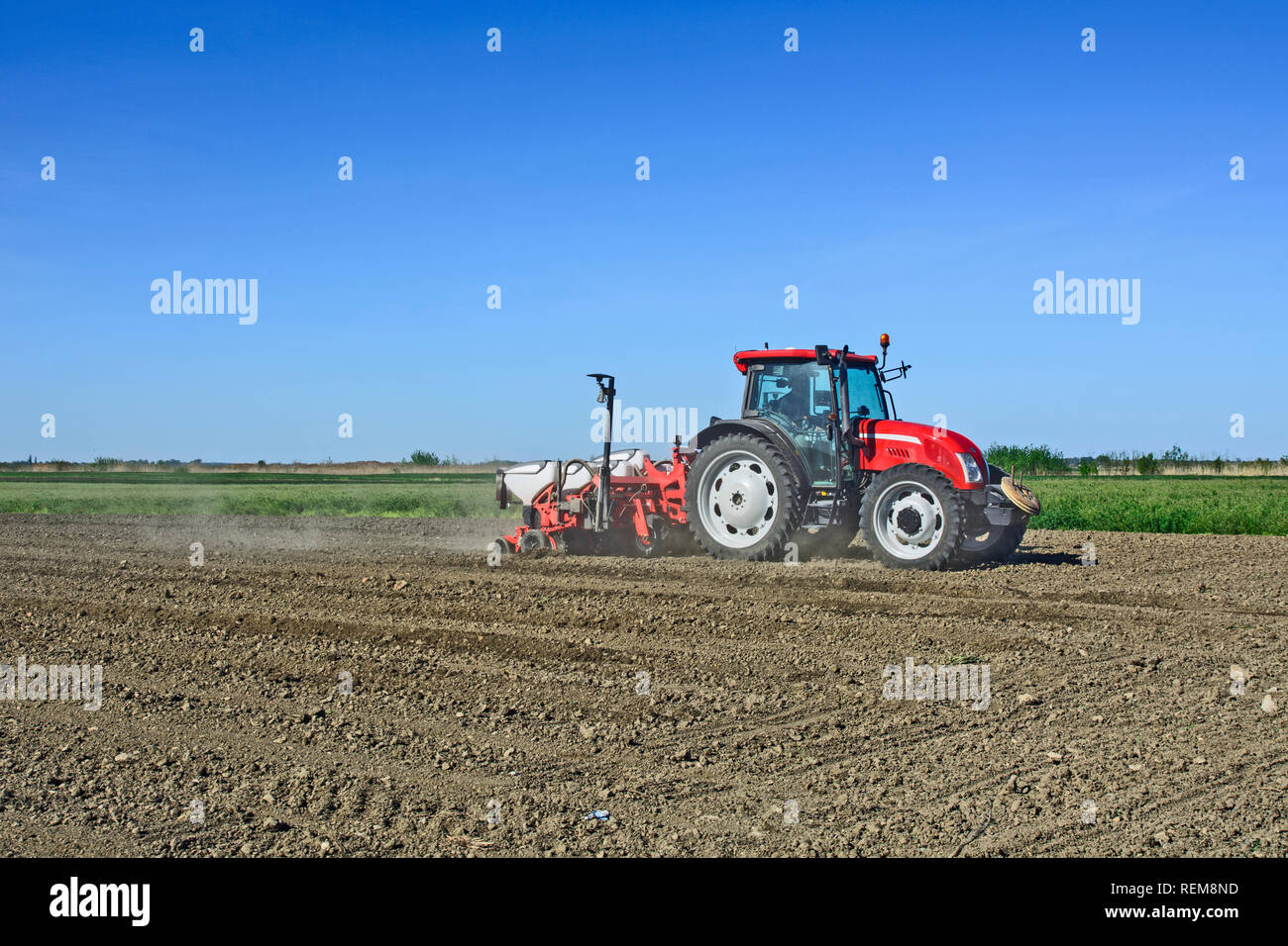 Spring sowing. Farmer with a tractor sows corn on his field Stock Photo ...
