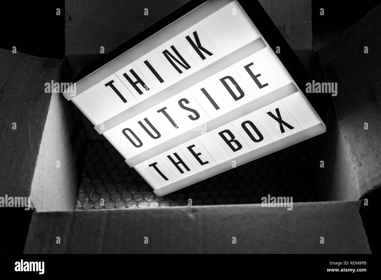 Think outside the box message on lightbox coming out of a parcel ...