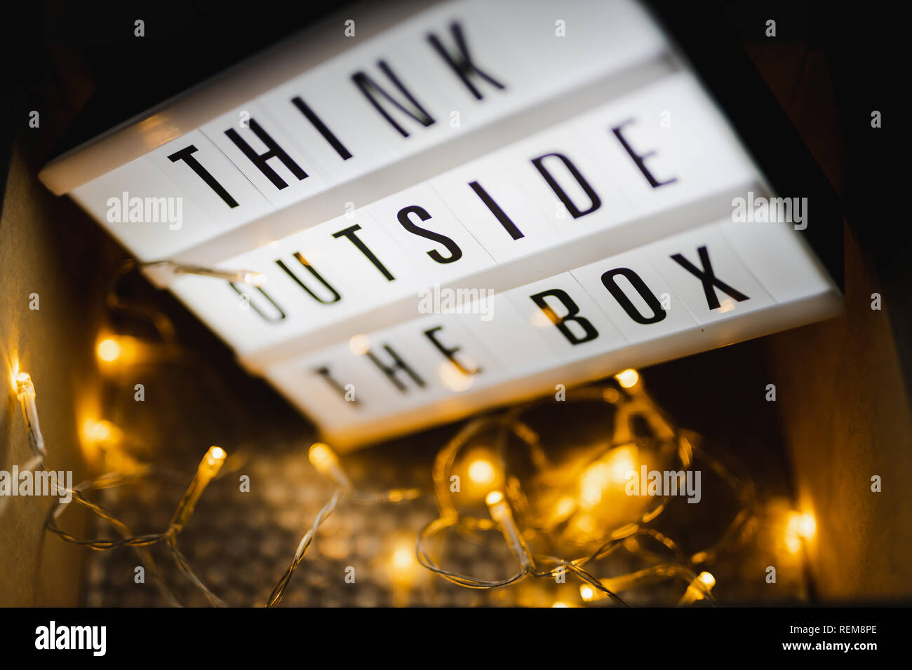 Think outside the box message on lightbox coming out of a parcel with ...
