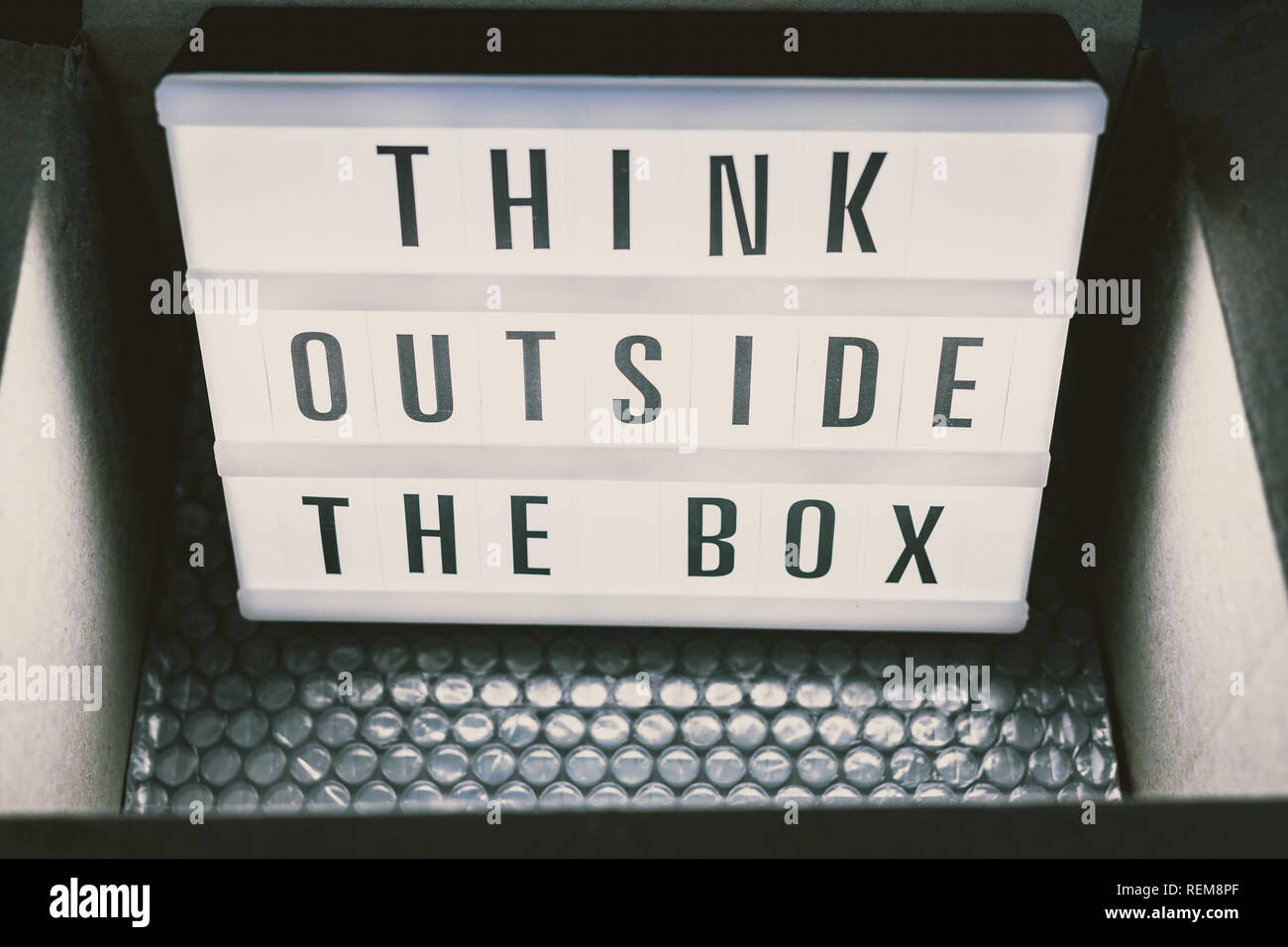 Think outside the box message on lightbox coming out of a parcel ...