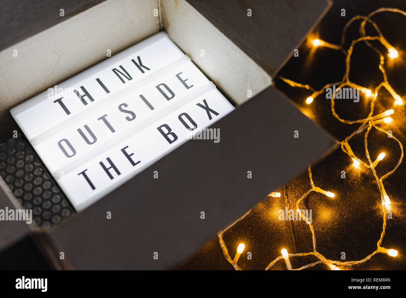 Think outside the box message on lightbox coming out of a parcel with ...