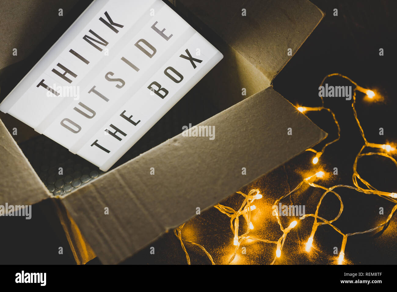 Think outside the box message on lightbox coming out of a parcel with ...