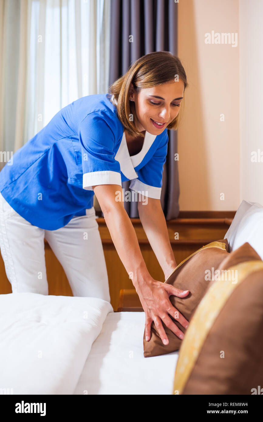 Maid making bed in hotel room Stock Photo - Alamy