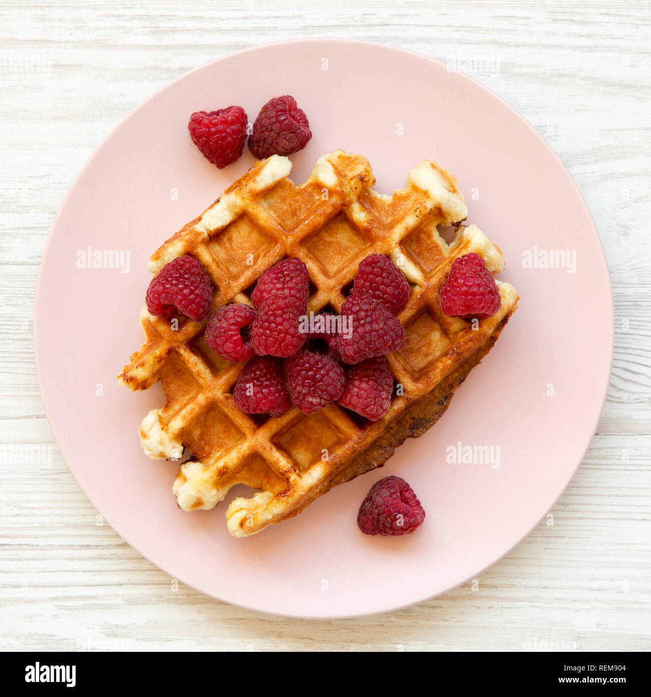 Traditional belgian waffle with raspberries on pink plate on white ...