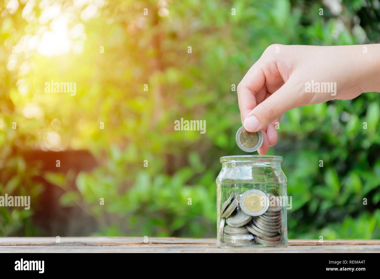 Money saving concept. close up hand coin catch into glass bottle ...