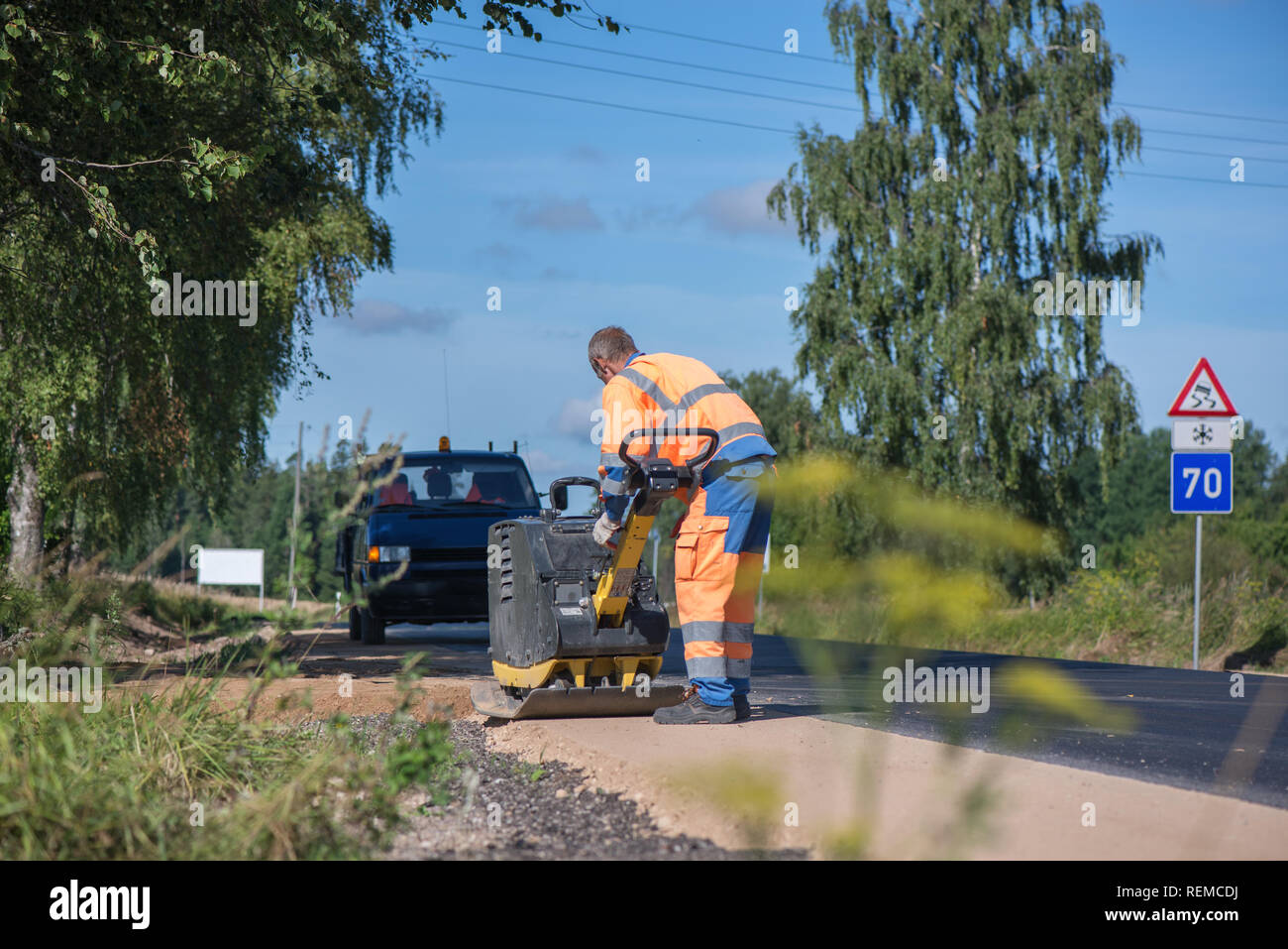 Manual road repair vibrating machine being pushed by a worker during ...