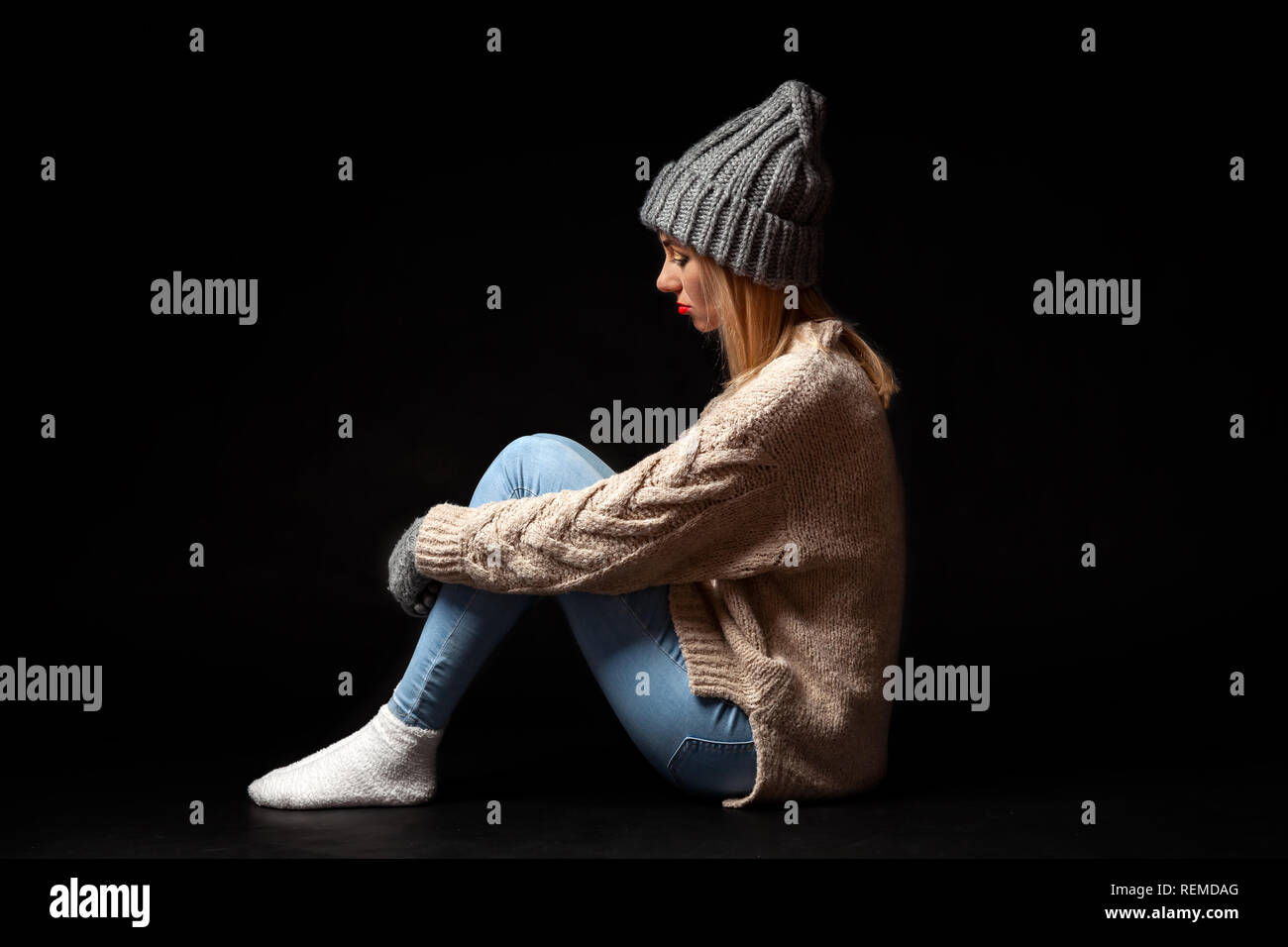 The girl is sitting alone on the floor on a black background of ...