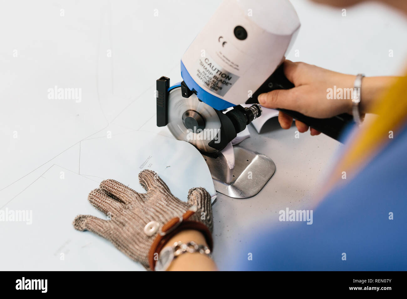 Woman cutting a textile pattern with a textile saw Stock Photo - Alamy