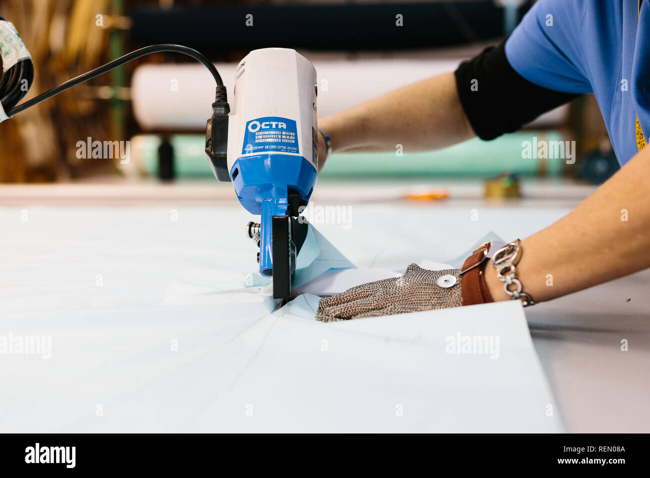 Woman cutting a textile pattern with a textile saw Stock Photo - Alamy