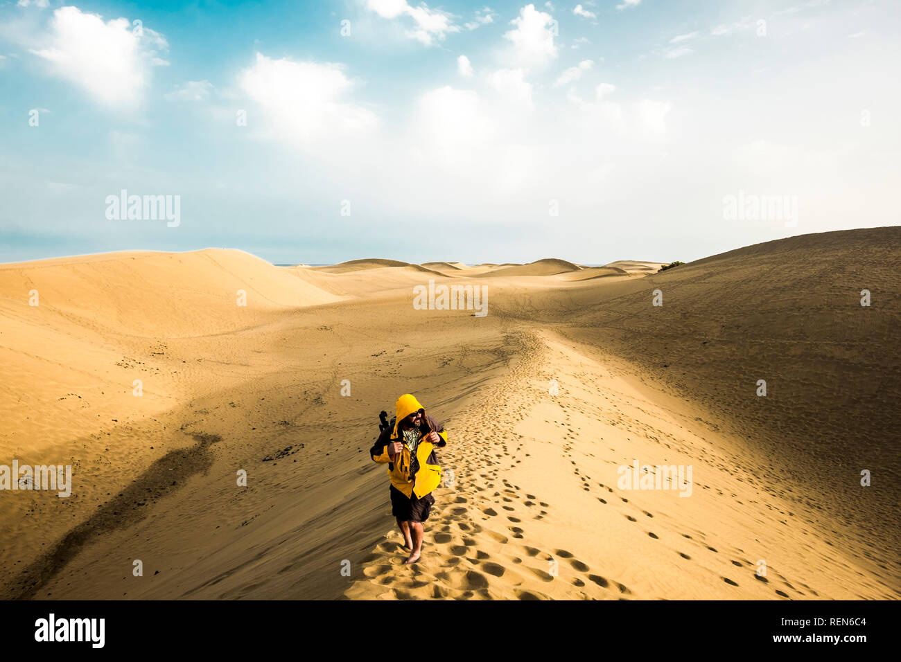 Adventurer lonely hiker in sand desert with infinite in background ...