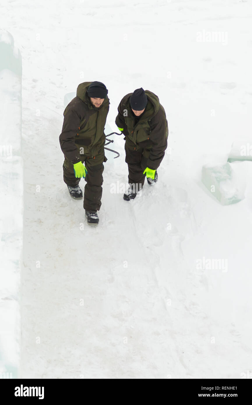 Two workers are pulling an ice block around the ice camp assembly site ...