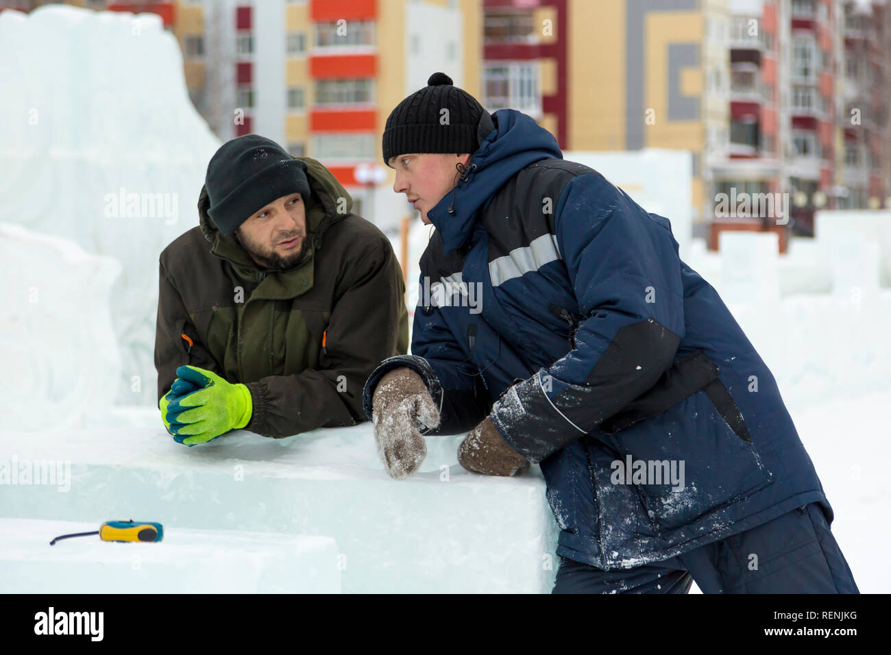 Workers assemblers mark the ice block on the construction site of the ...
