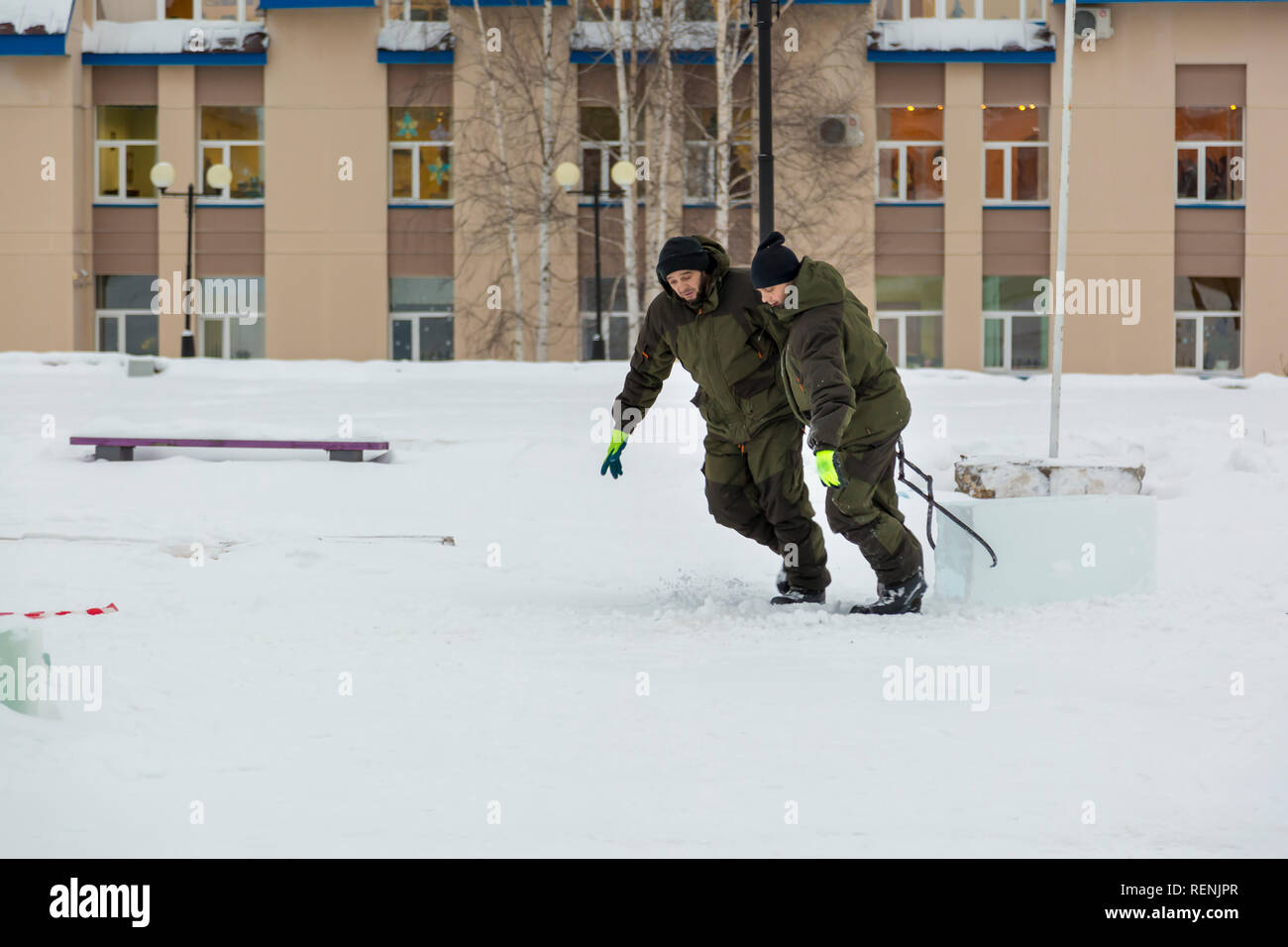 Two workers are pulling an ice block around the ice camp assembly site ...