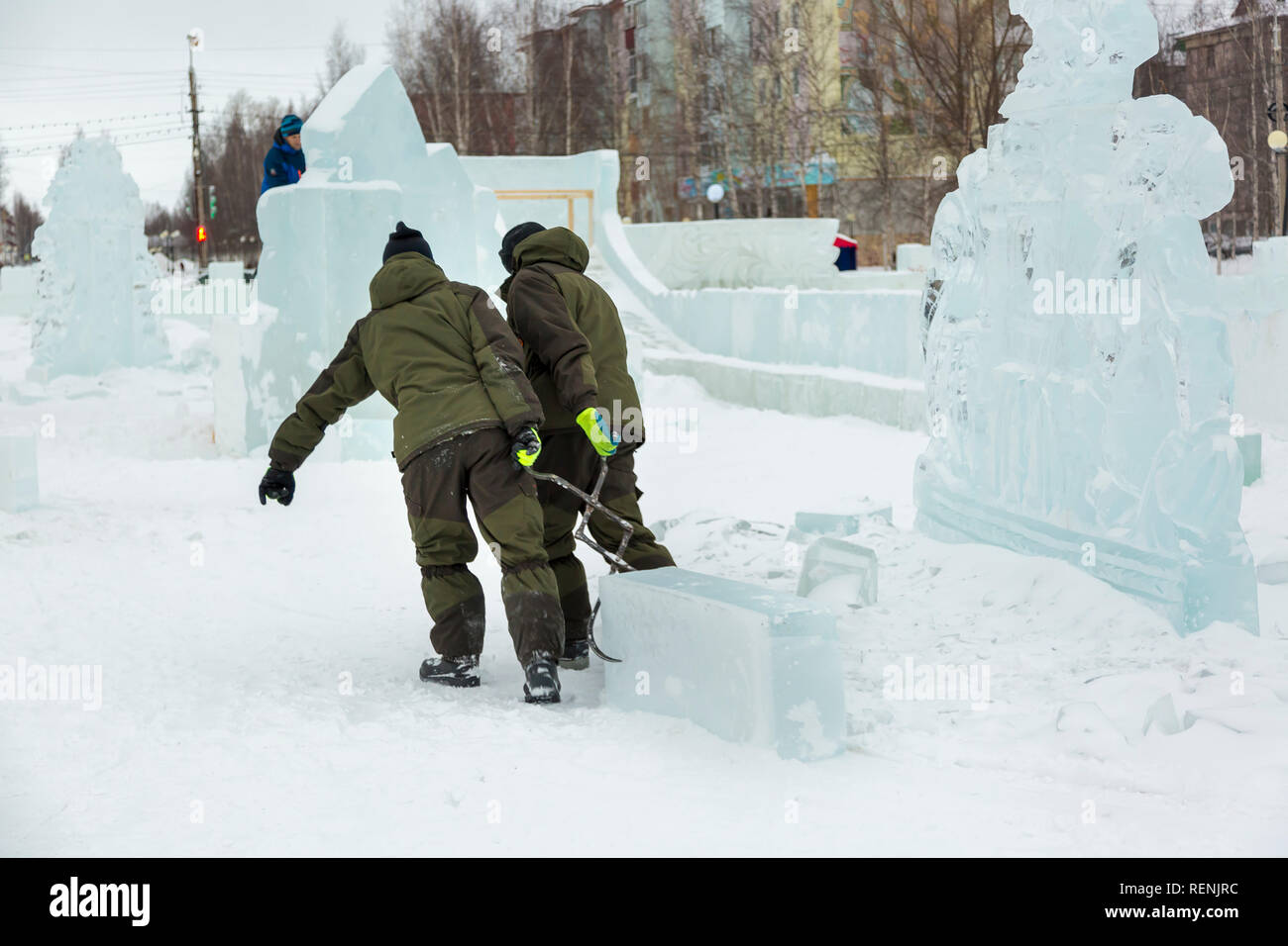 Two workers are pulling an ice block around the ice camp assembly site ...