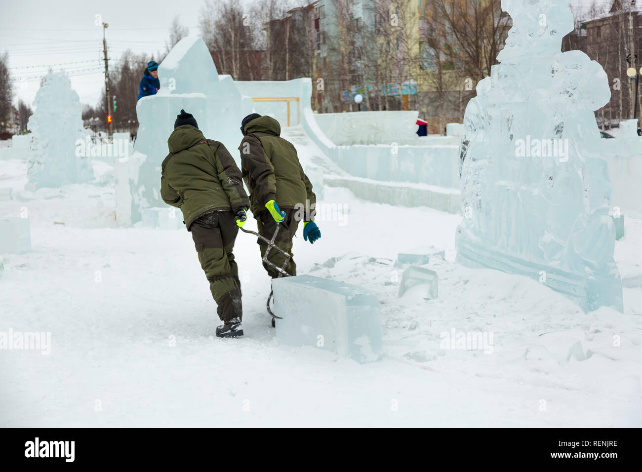 Two workers are pulling an ice block around the ice camp assembly site ...