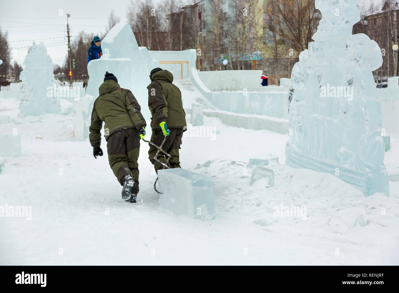 Two workers are pulling an ice block around the ice camp assembly site ...