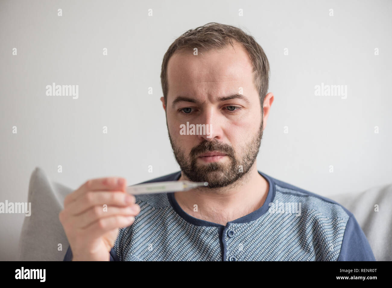 Sick man checks the body temperature with a mercury thermometer. Theme ...