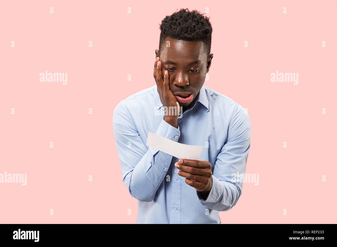 Young afro man with a surprised unhappy failure expression bet slip ...
