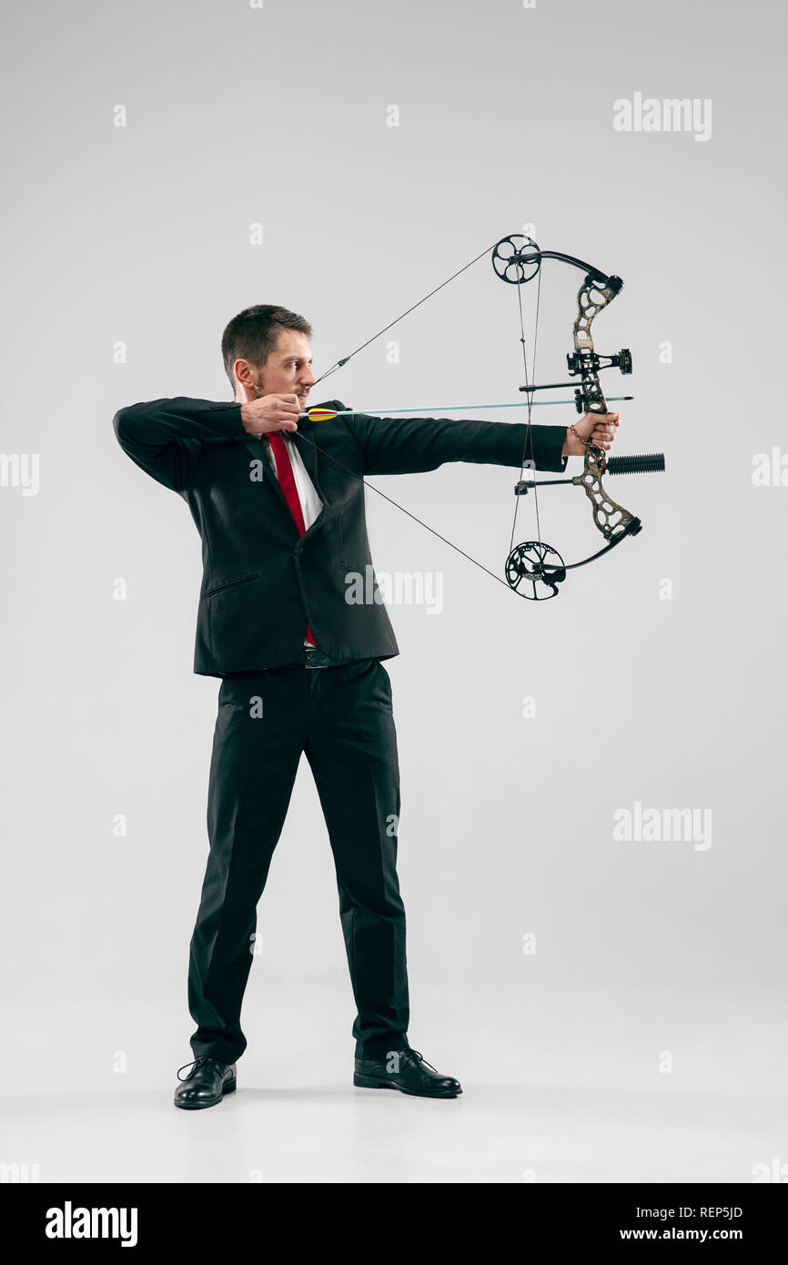 Businessman aiming at target with bow and arrow, isolated on gray ...