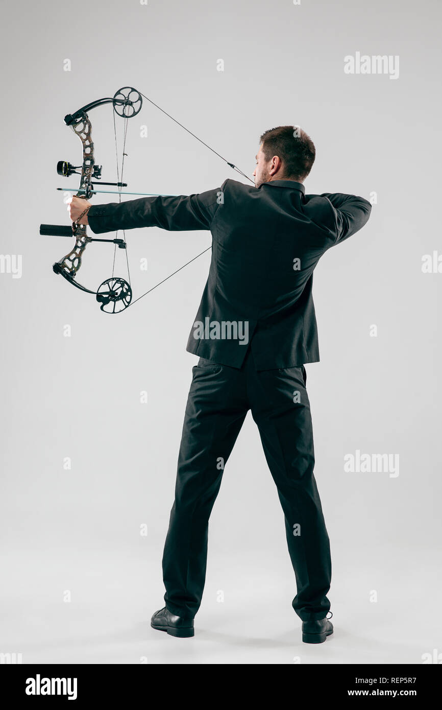 Businessman aiming at target with bow and arrow, isolated on gray ...