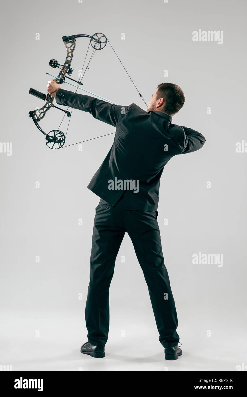 Businessman aiming at target with bow and arrow, isolated on gray ...