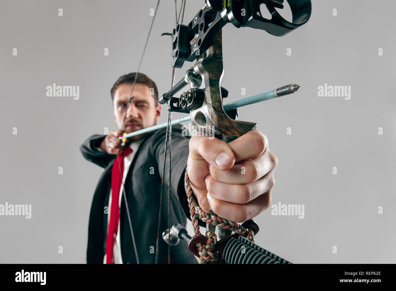 Businessman aiming at target with bow and arrow, isolated on gray ...