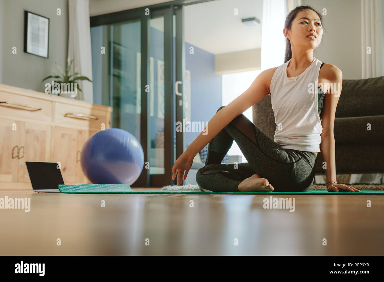 Healthy woman sitting on exercise mat and doing yoga. Asian woman ...