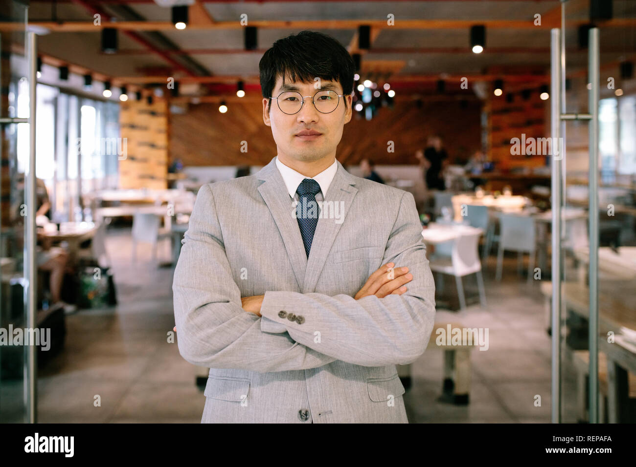 Portrait of successful businessman standing at coffee shop door. Korean ...