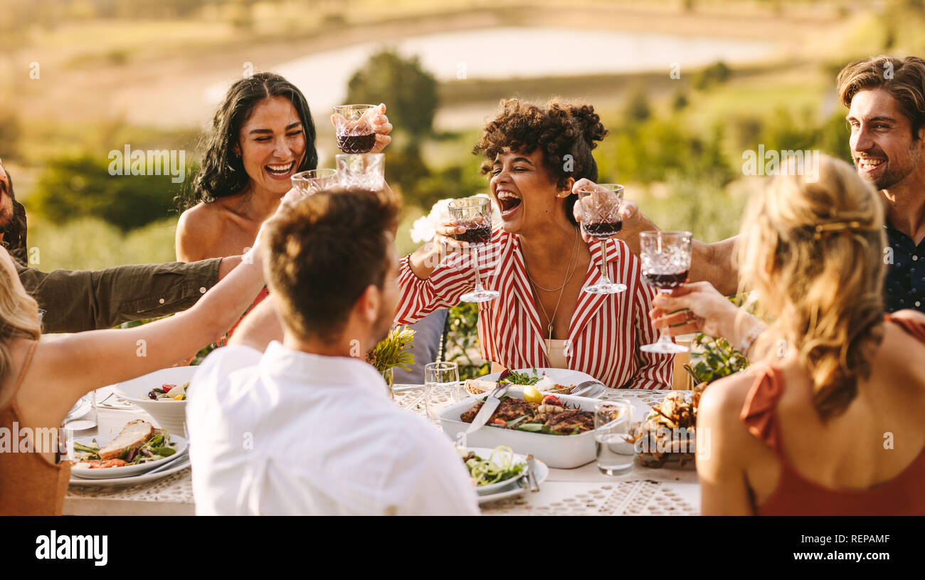 Group of cheerful friends having wine at dinner party. Multi-ethnic ...