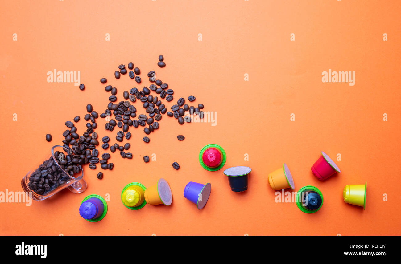 Coffee beans and capsules, pods, on bright orange color background ...