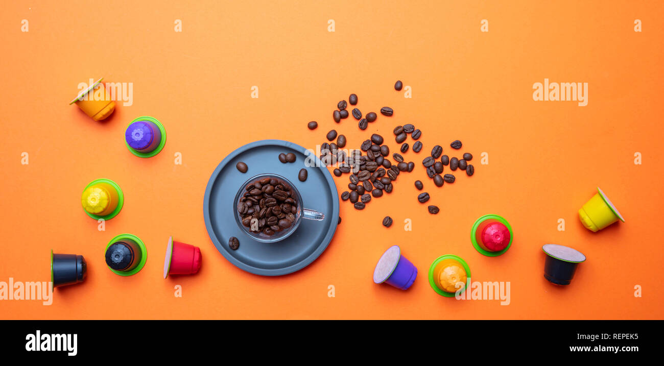 Coffee cup, beans and capsules, pods, on bright orange color background ...