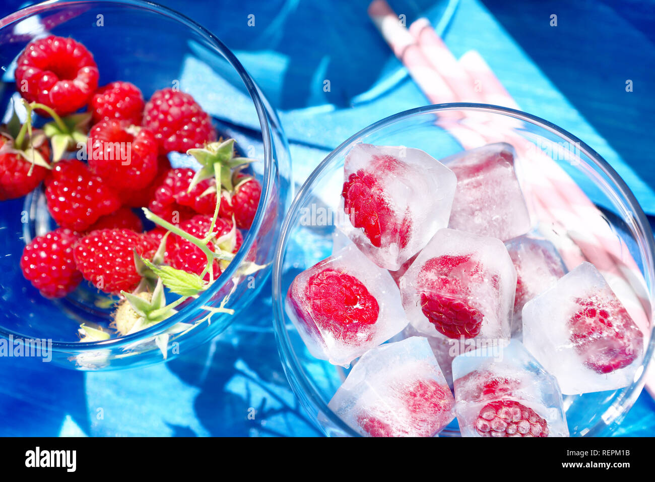 Frozen raspberries in ice cubes in a blue background Stock Photo - Alamy