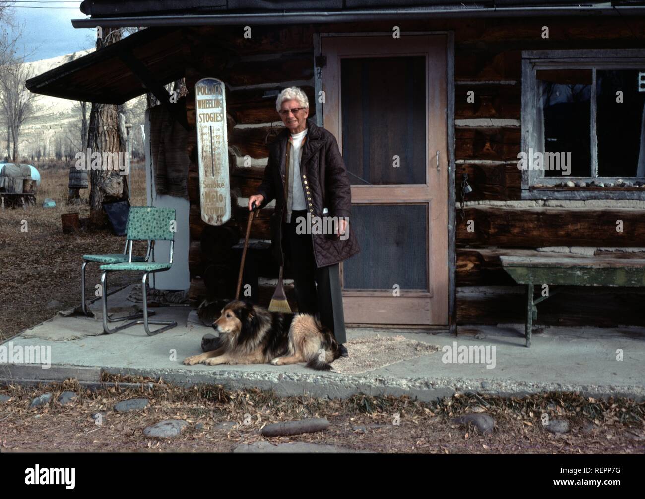 A mature woman stands outside a small wooden cabin on a camping trip ...