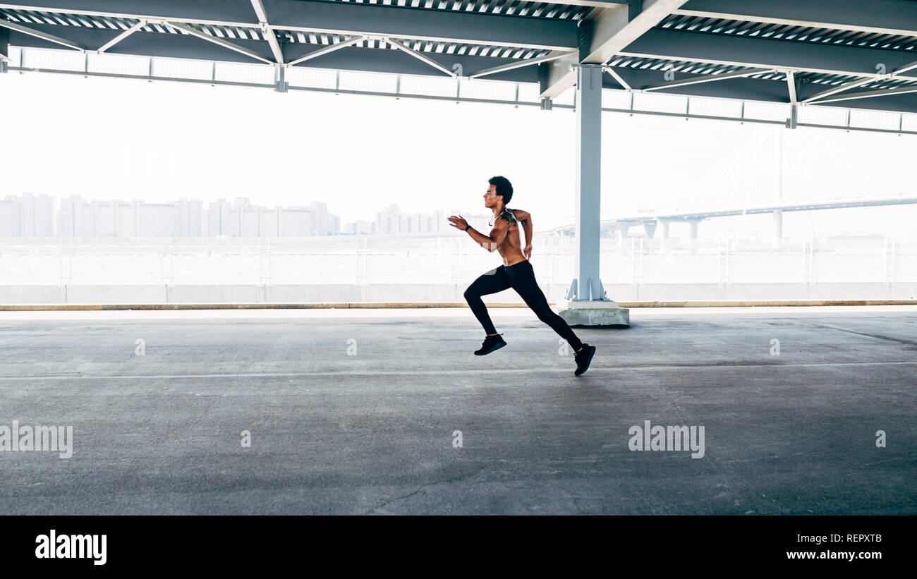Side view of man sprinting under a bridge Stock Photo - Alamy