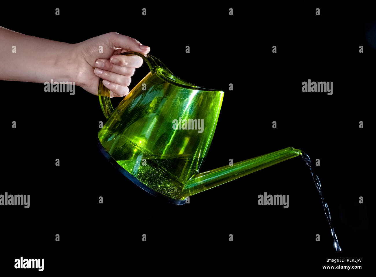 green watering can in hand with pouring water on black background Stock ...